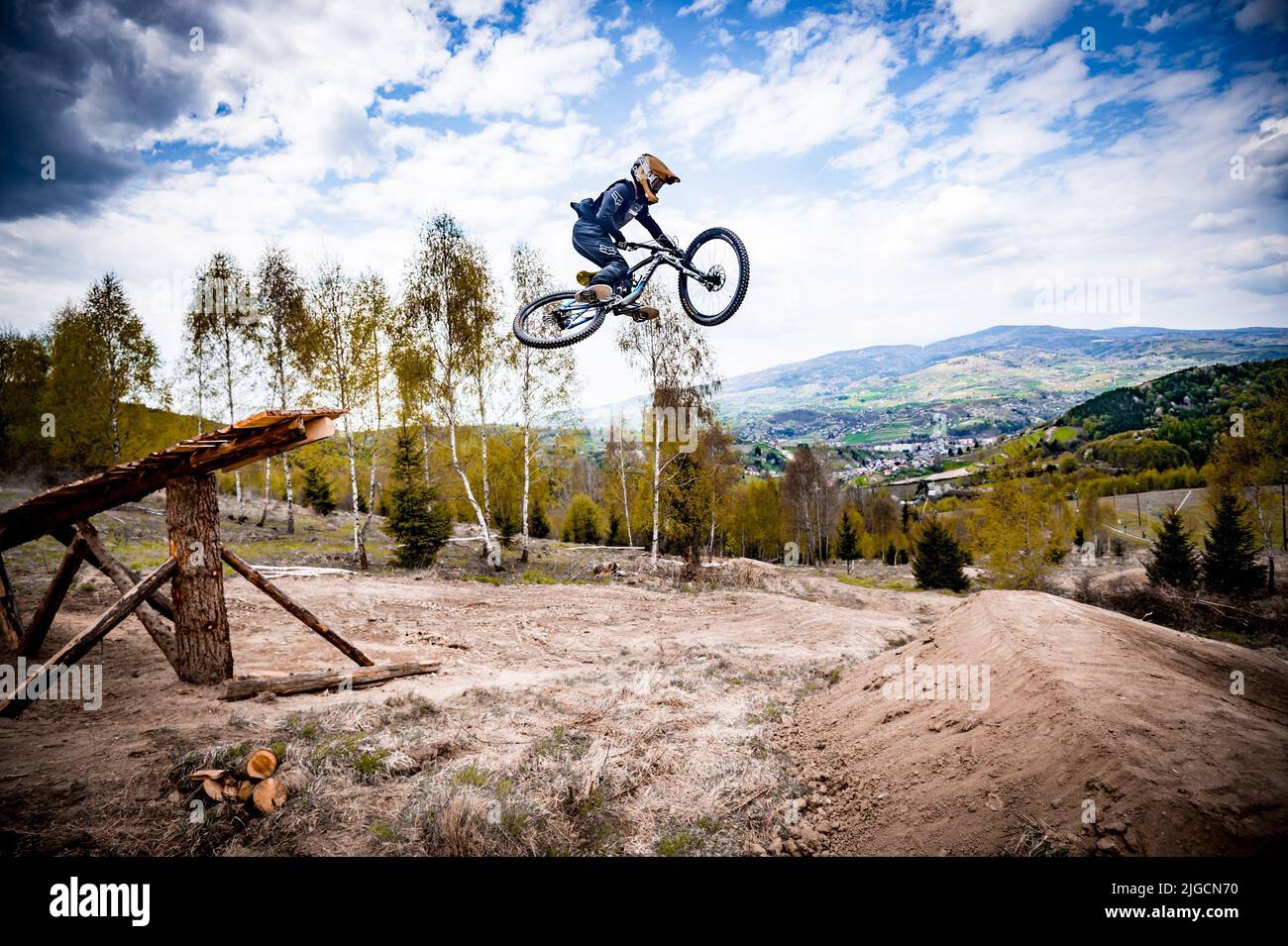 A male rider in a helmet on a bike doing an extreme jump over a track ...