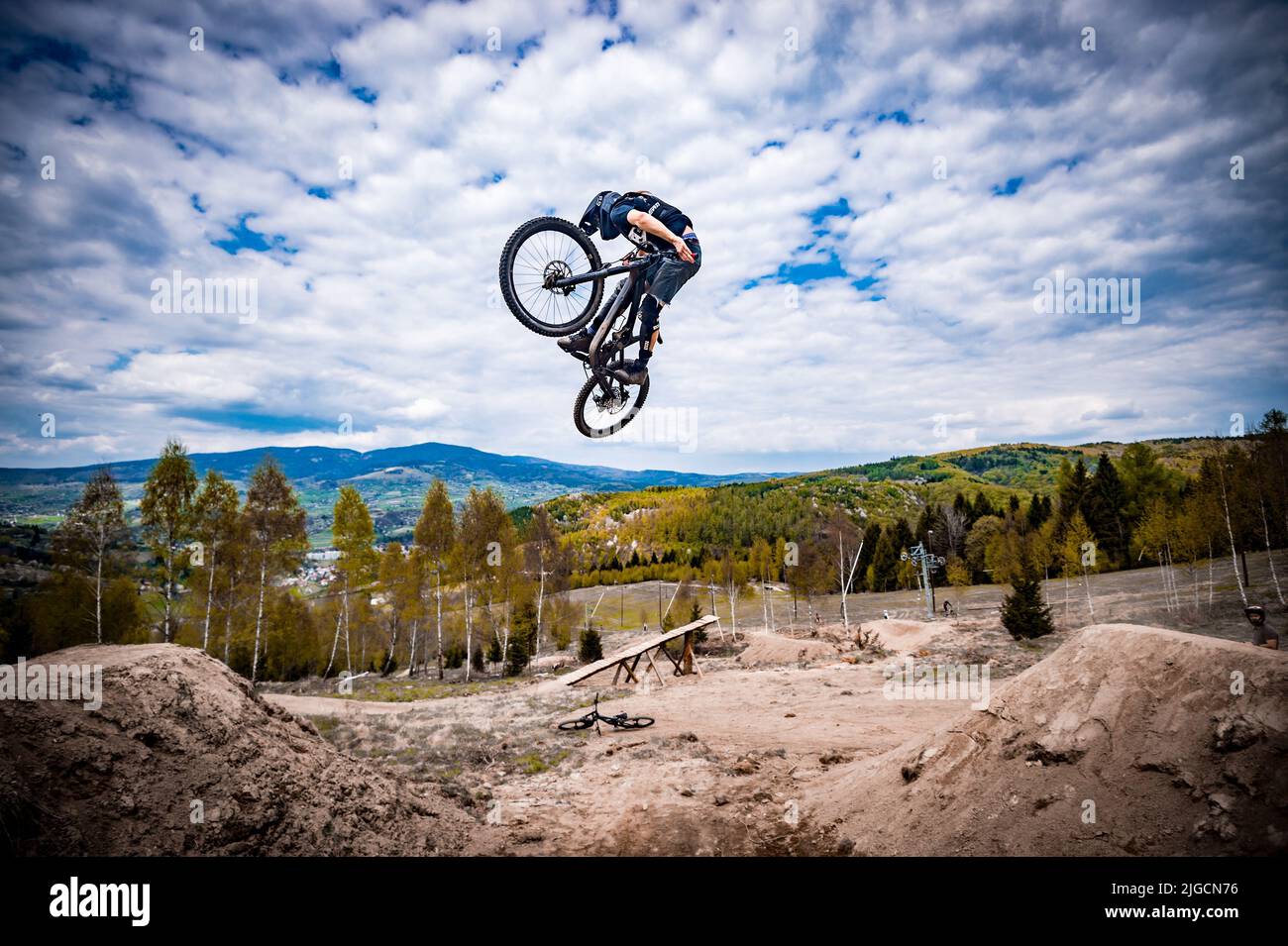 A male rider in a helmet on a bike doing an extreme jump over a track ...