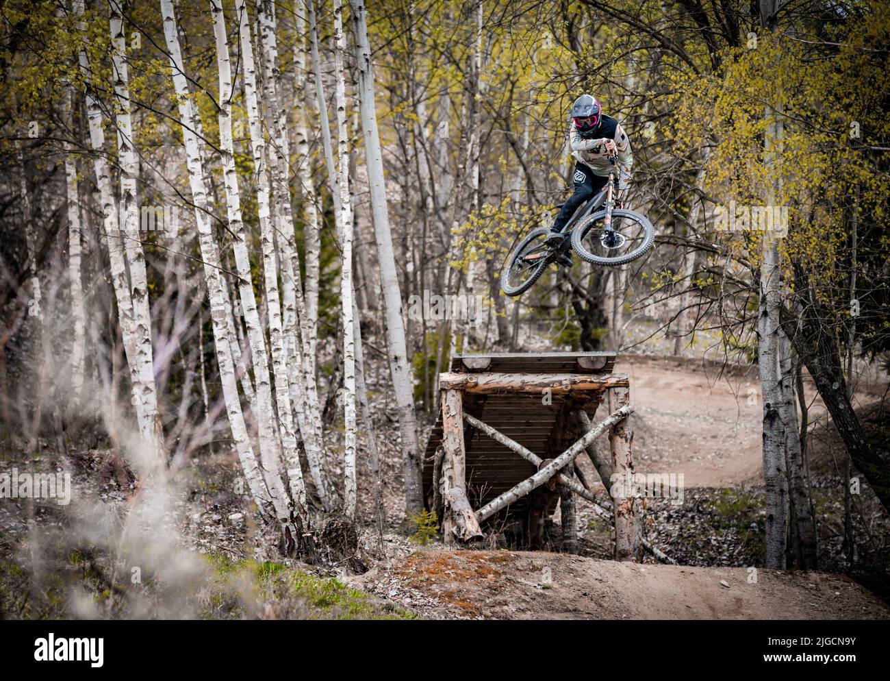 A male rider in a helmet on a bike jumping over a wooden ramp at a bike ...