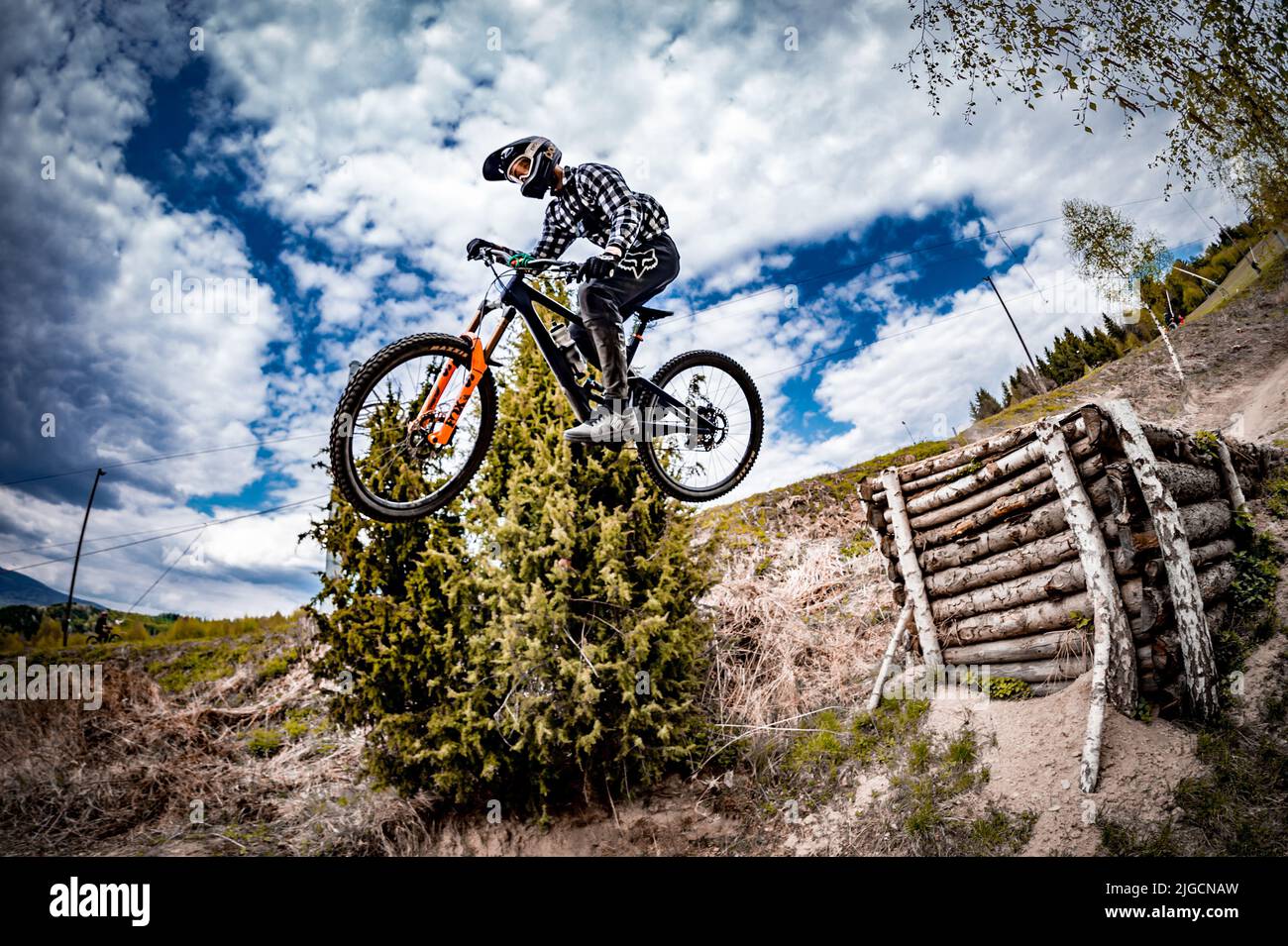 A male rider in a helmet doing an extreme jump on a bike over a track ...