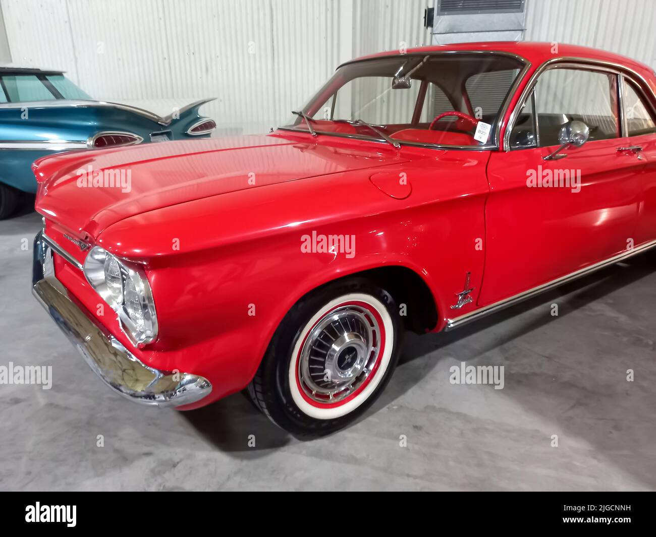 Old red Chevrolet Chevy Corvair Monza coupe 1963 in a warehouse. Side ...