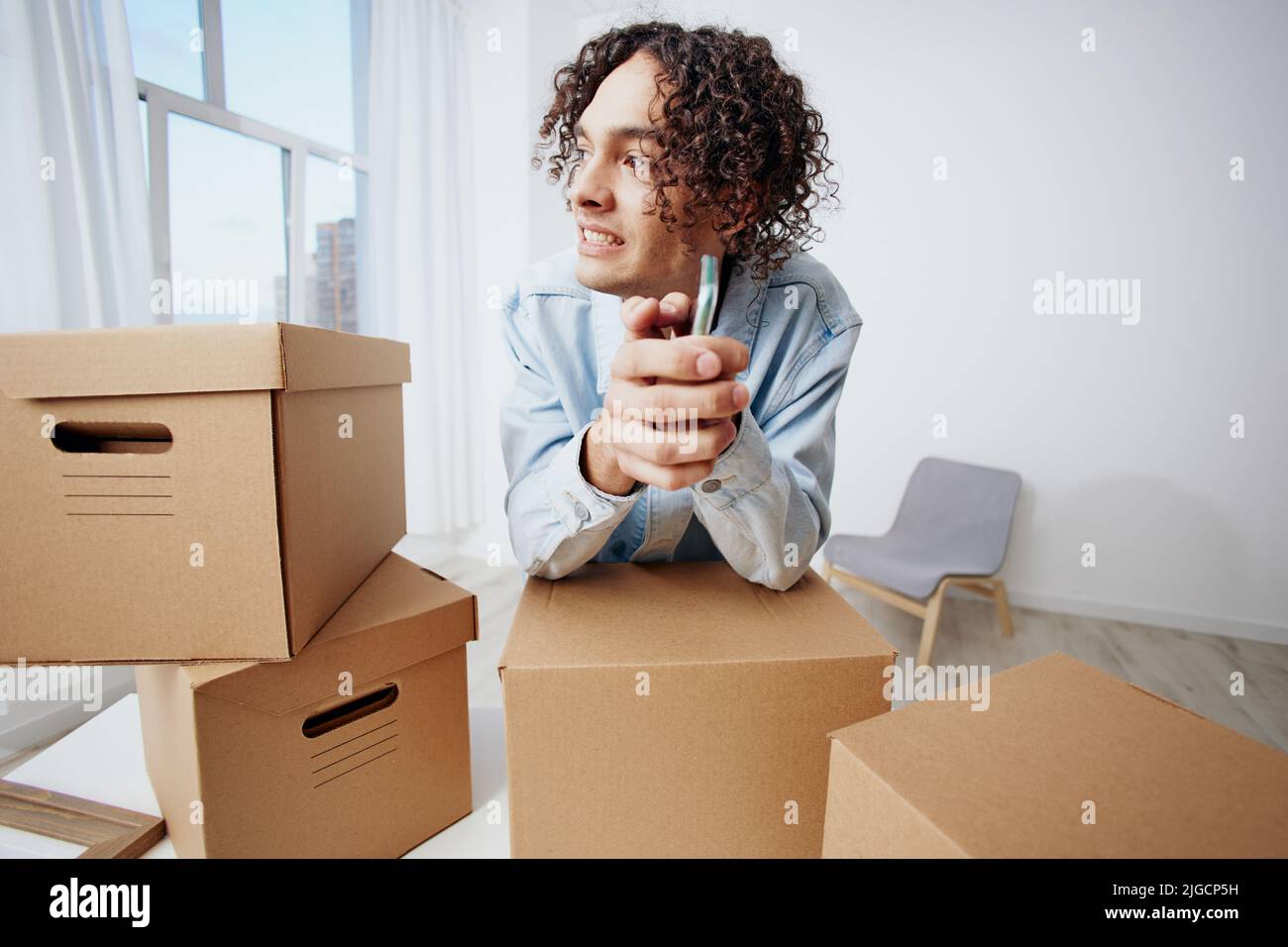 guy with curly hair unpacking things from boxes in the room sorting ...