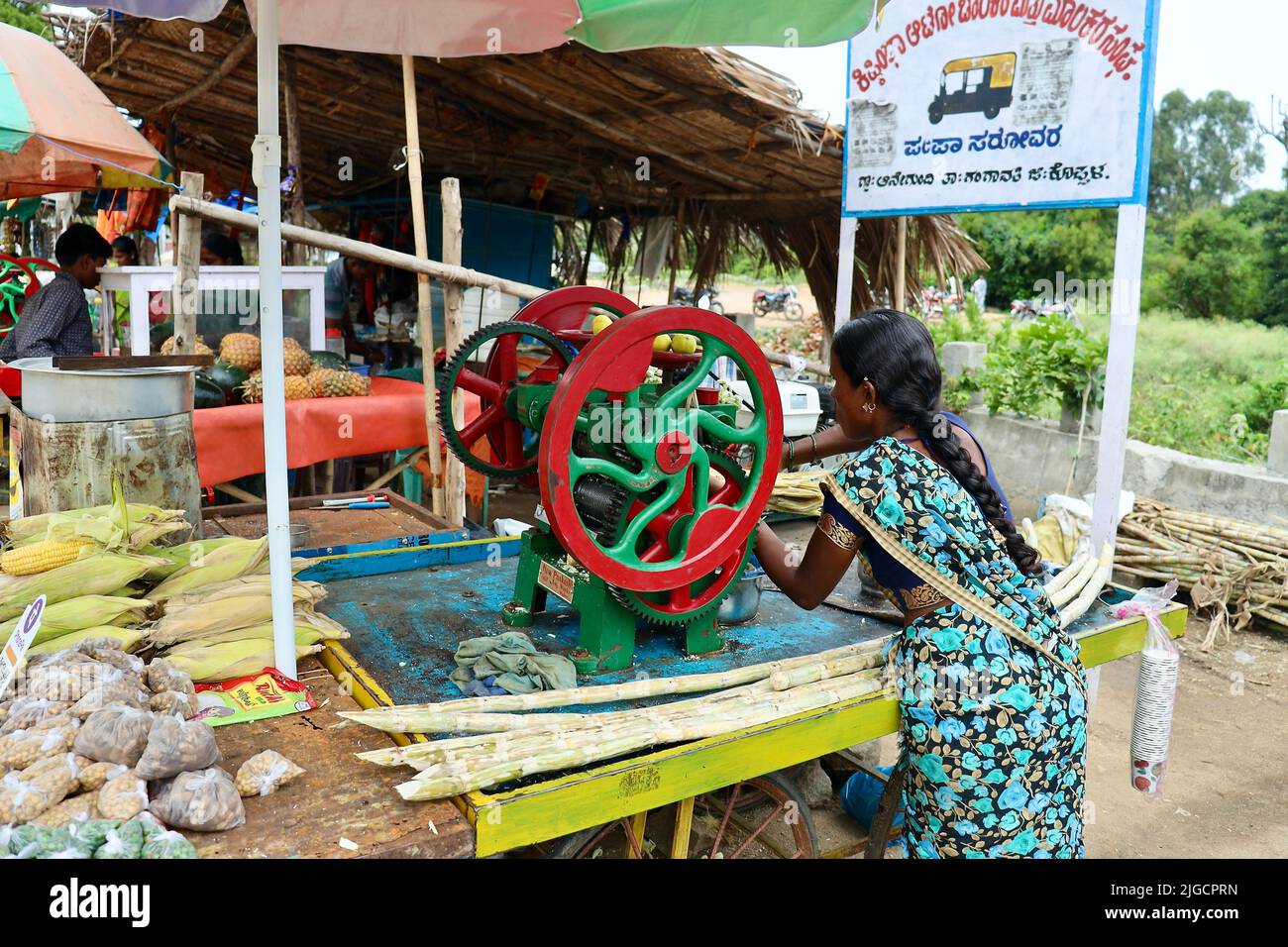 A selective focus of a poor Indian village lady brewing sugar cane ...