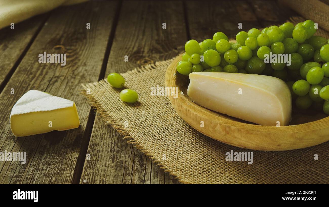 rustic cheese and green grapes on a wooden table in a farm Stock Photo ...