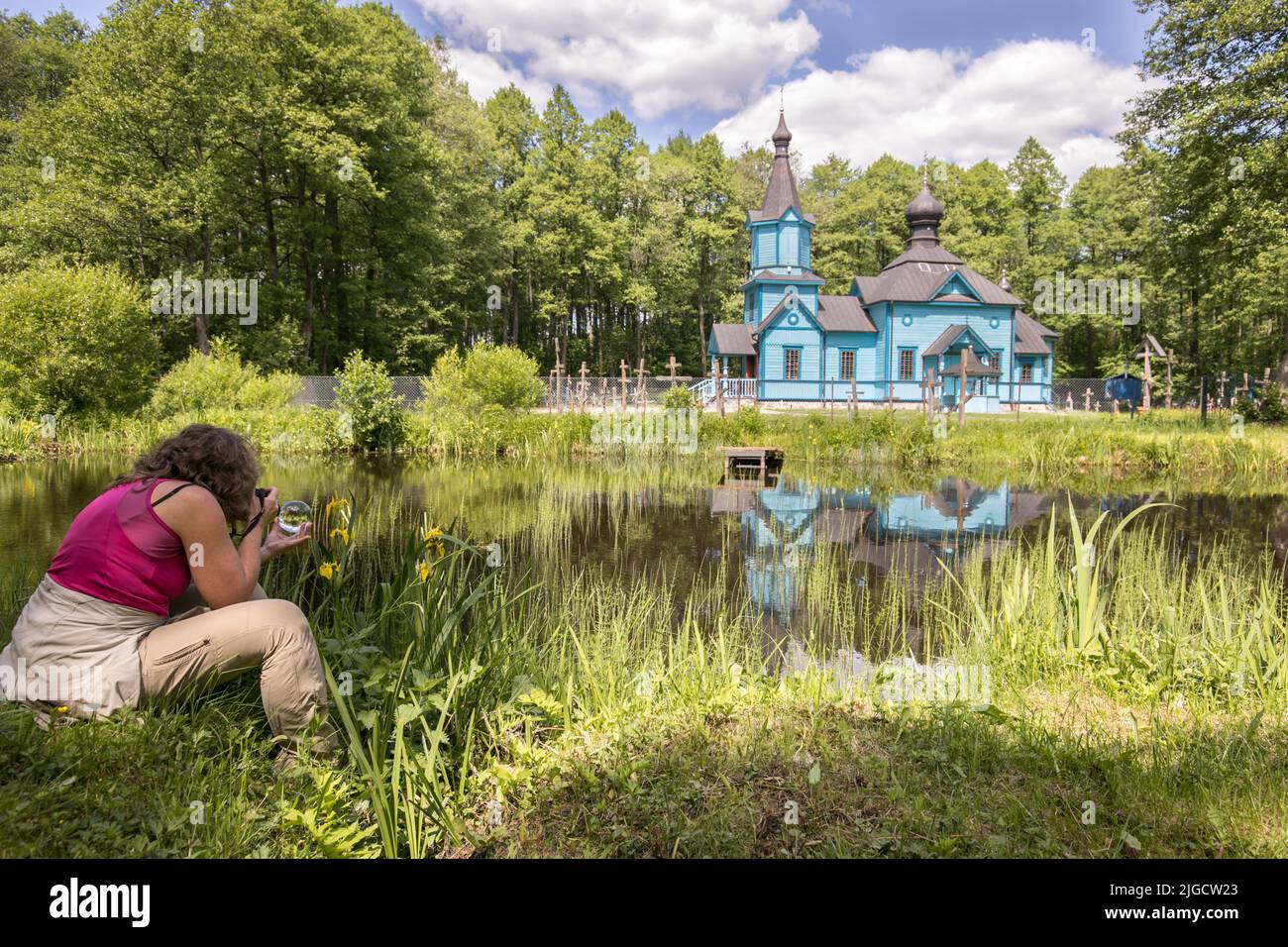 A woman takes picture of blue, wooden orthodox church. Podlasie ...