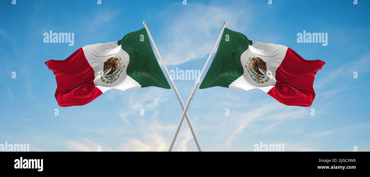 two crossed flags Mexico and mexico waving in wind at cloudy sky ...
