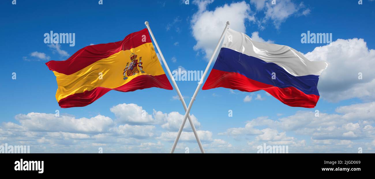 two crossed flags Russia and spain waving in wind at cloudy sky ...