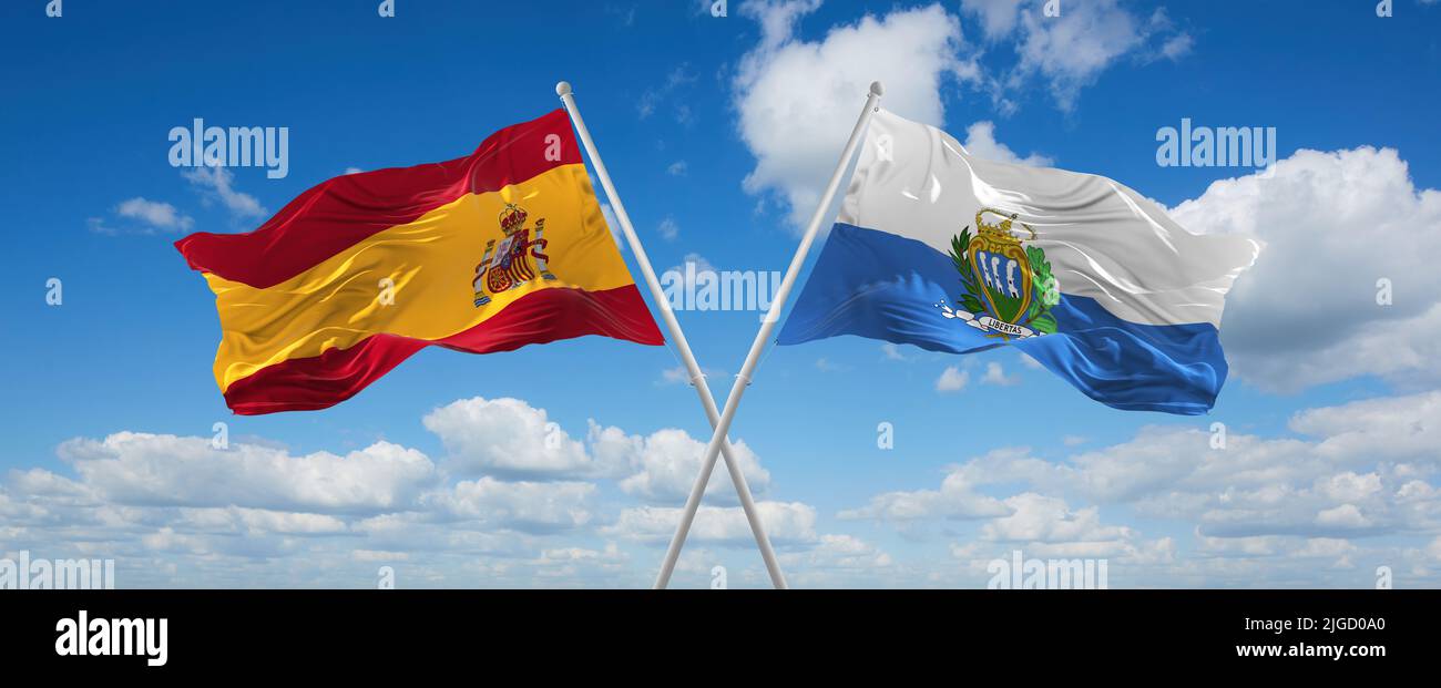 two crossed flags San Marino and spain waving in wind at cloudy sky ...