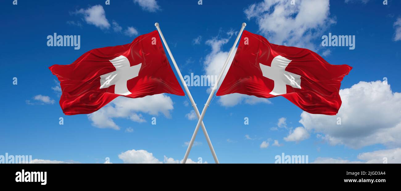 two crossed flags switzerland and Switzerland waving in wind at cloudy ...