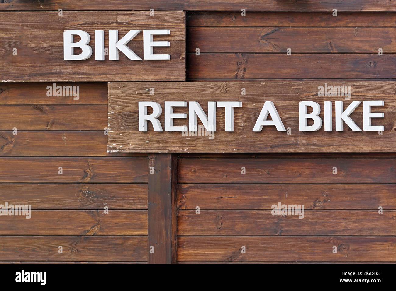 Rent a bike sign at wooden cabin wall Stock Photo - Alamy