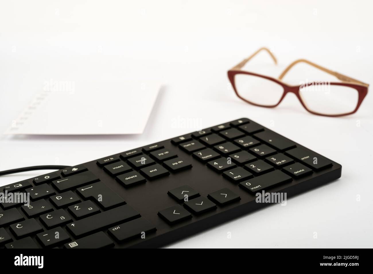 A top view of Computer Keyboard, notes and glasses on a white ...