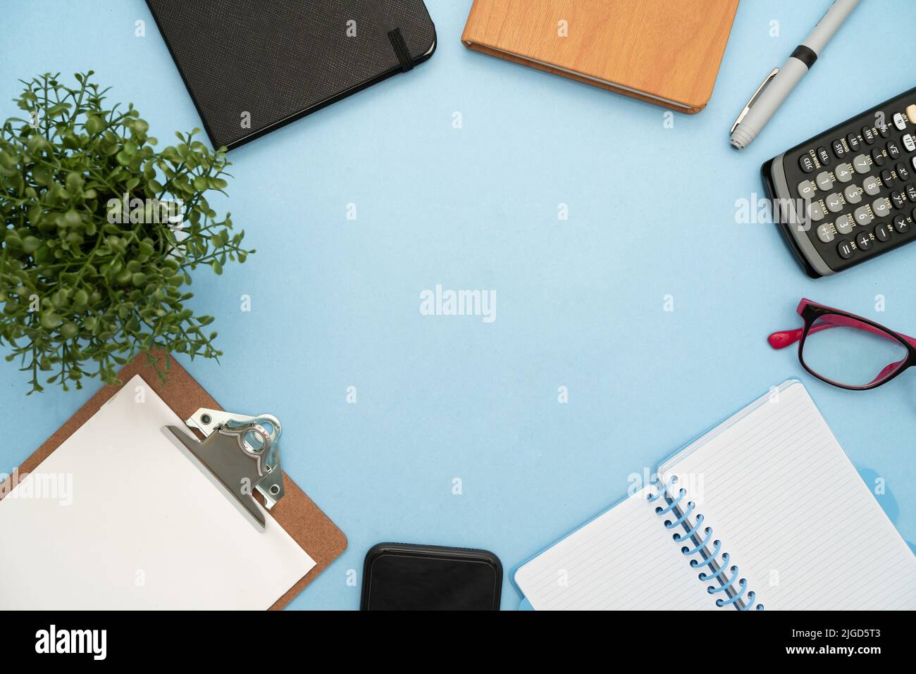 A top view of notes and documents with glasses and pen on a blue desk ...