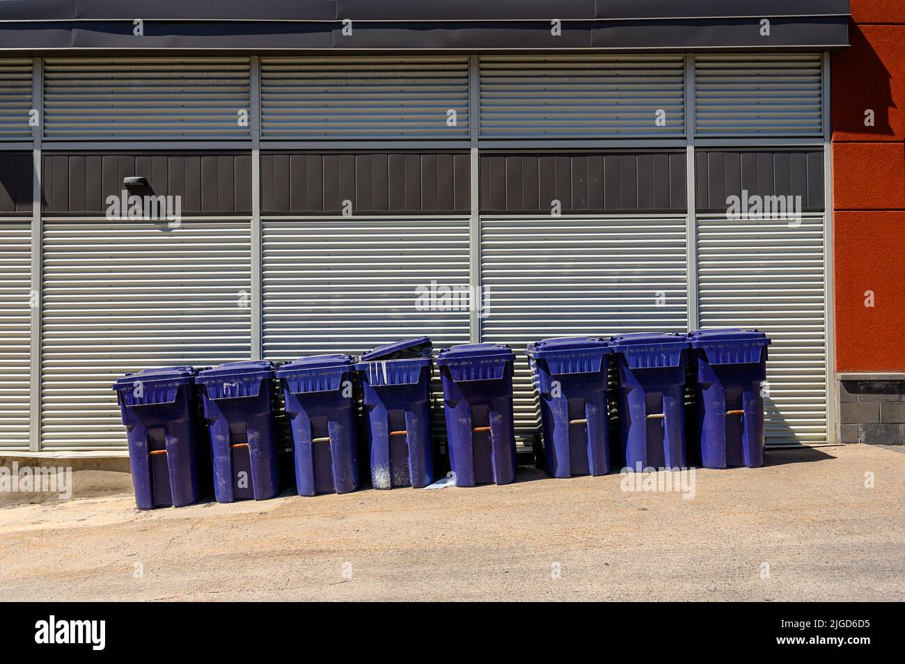 Blue Bins against warehouse wall Stock Photo - Alamy