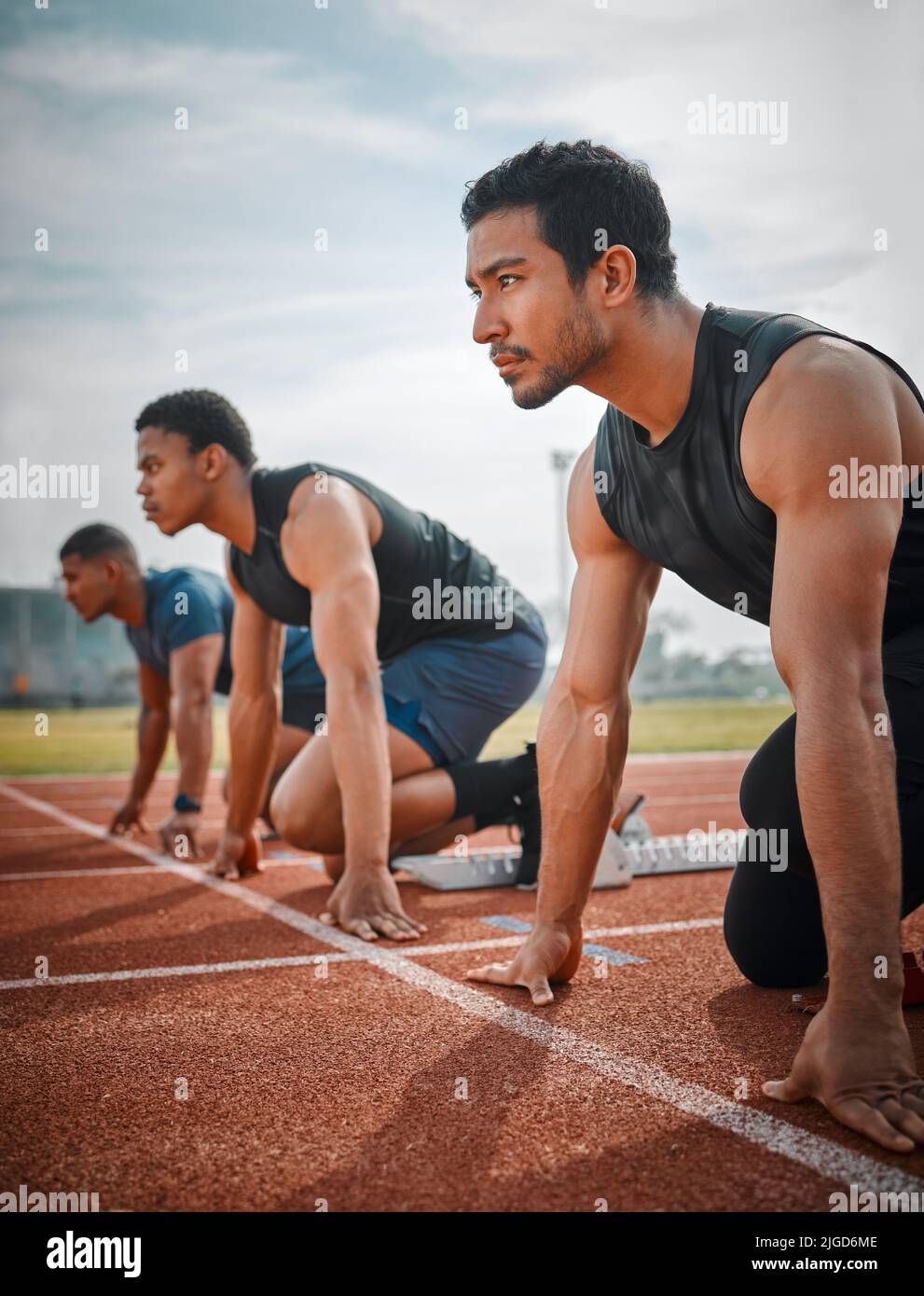 Focused on the finish line. three handsome young male athletes starting ...