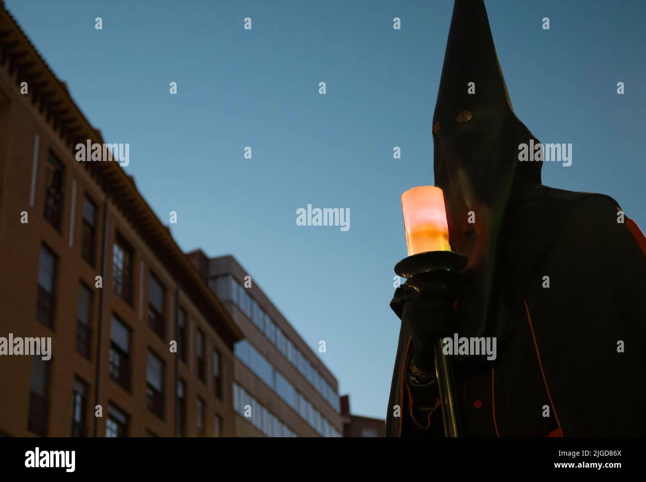 A confrere of the brotherhood in procession carrying a candle lit ...