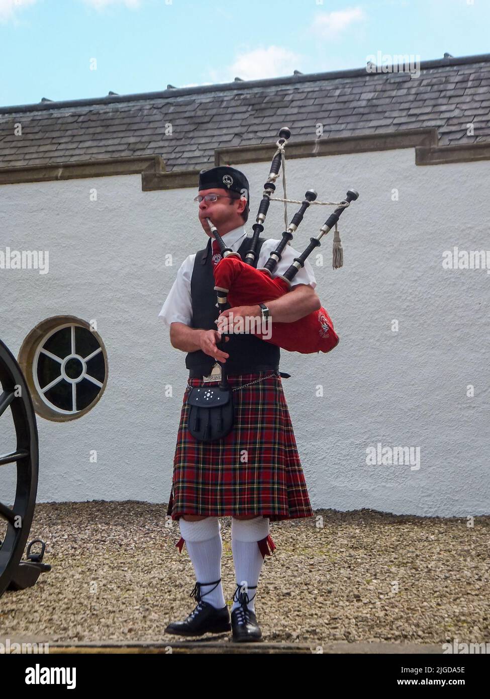 A uniformed piper plays bagpipes at Blair Castle in Pitlochry ...