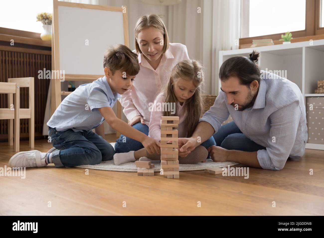 Focused engaged parents and two little kids playing board game Stock ...