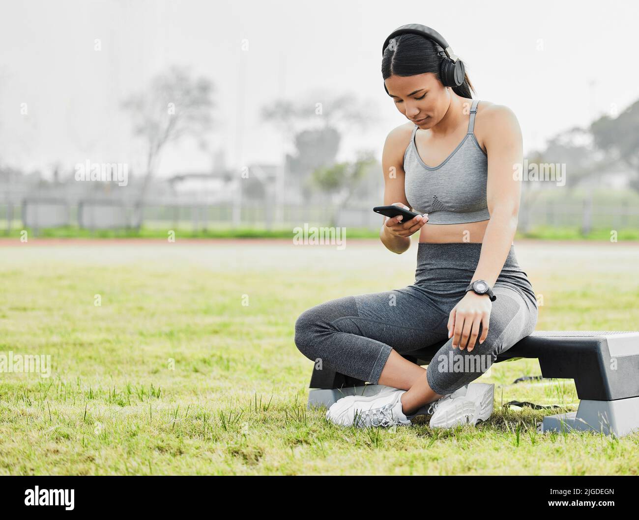 Looking for the perfect workout playlist. Full length shot of an attractive young female athlete ...