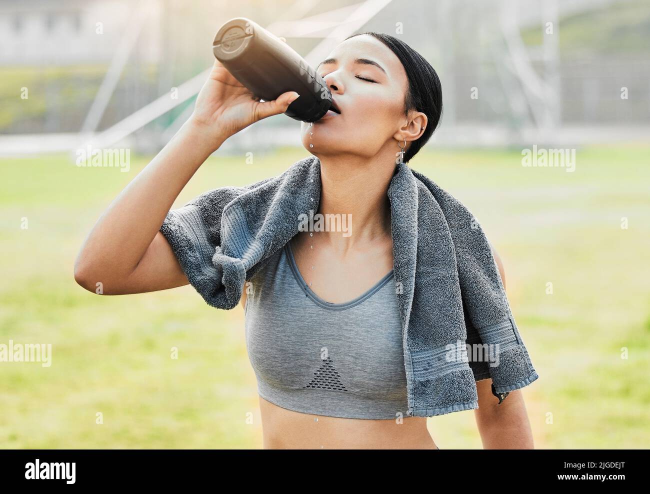 Staying hydrated. an attractive young female athlete drinking water ...