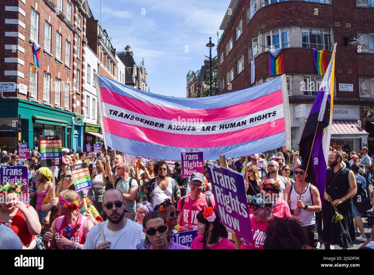 Protesters carry a banner with the colours of the Trans Pride flag ...