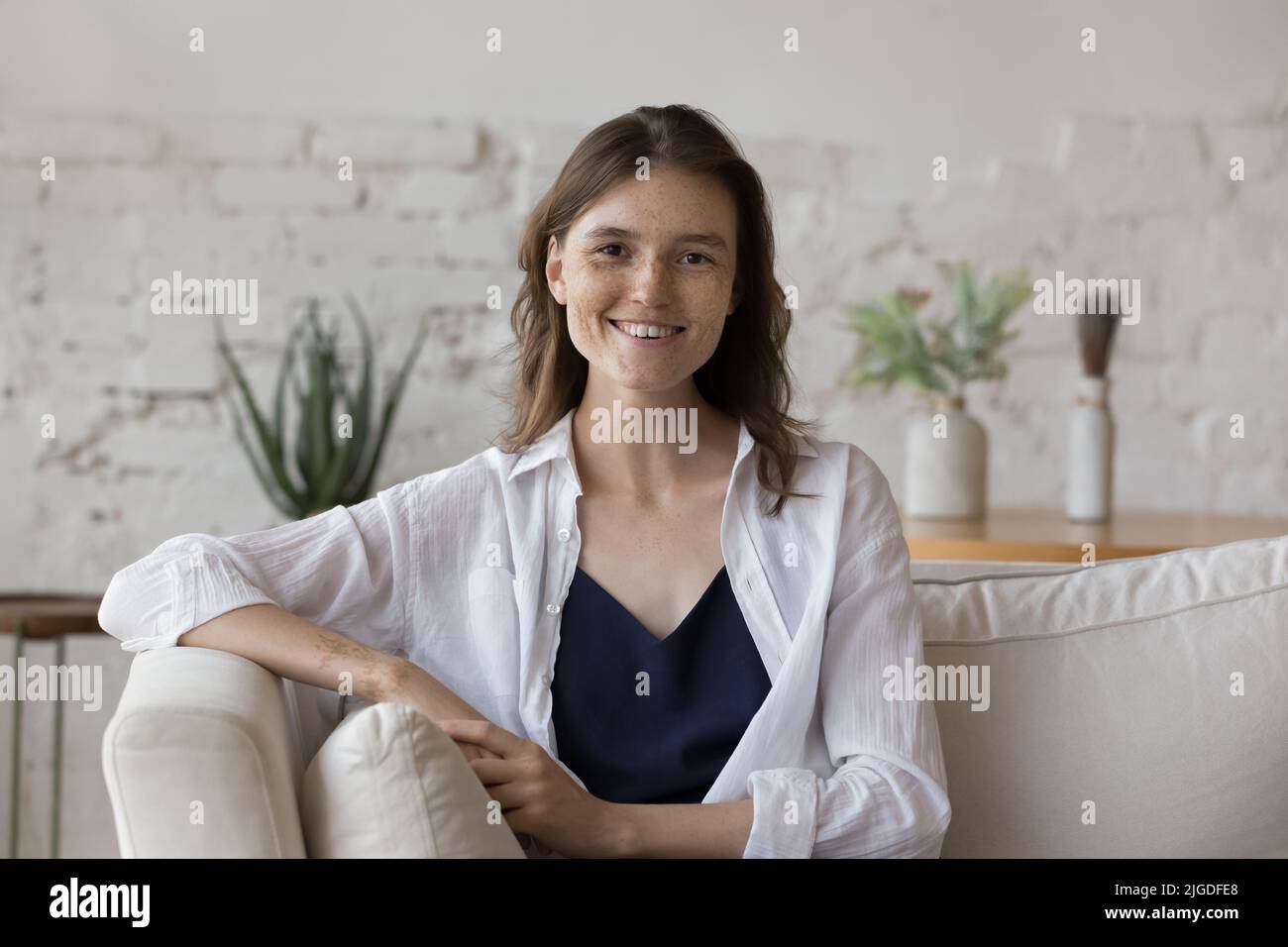 Pretty freckled woman sit on sofa smile staring at camera Stock Photo ...