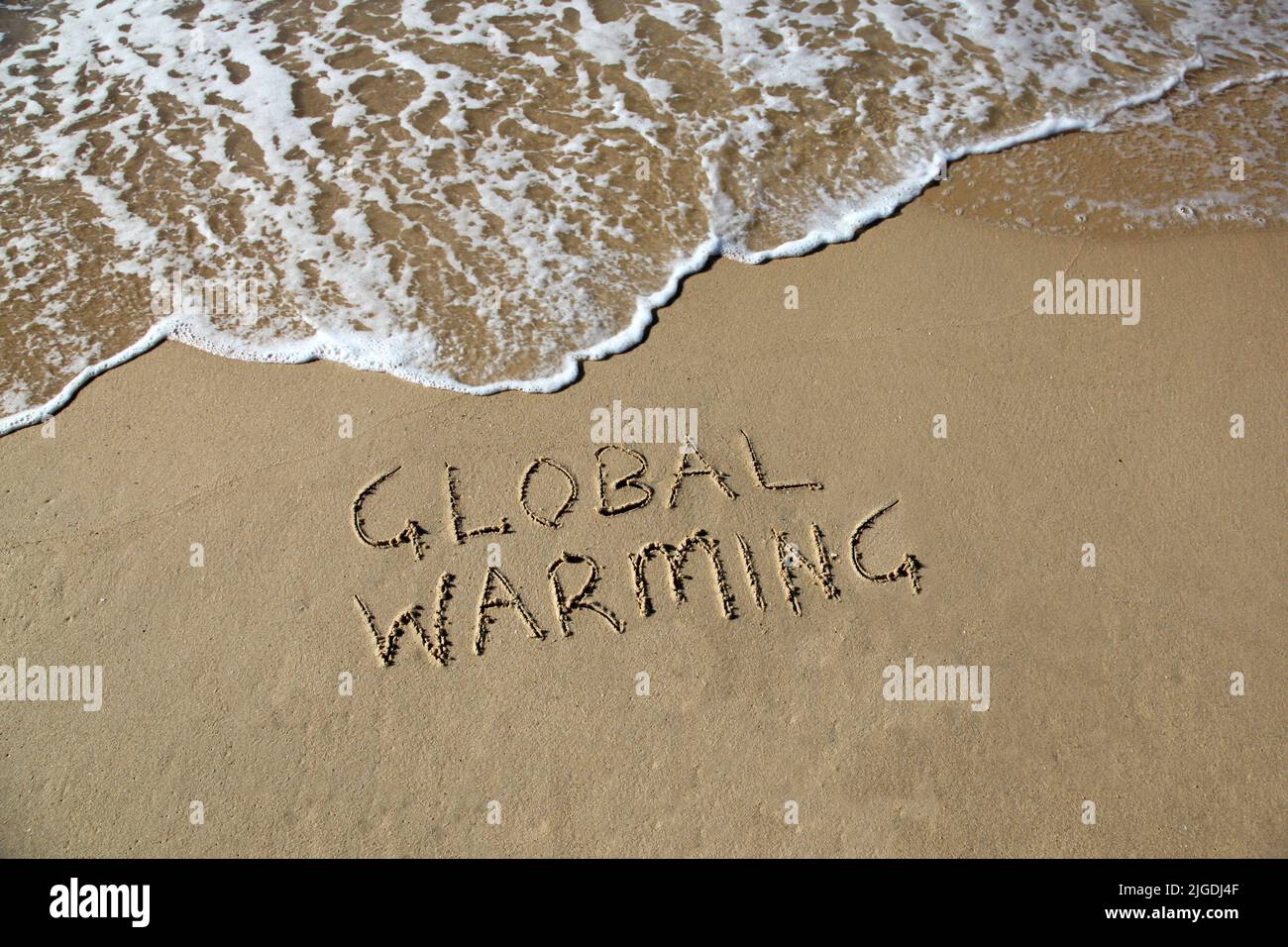 Global warming written in the sand at beach with rising wave Stock ...