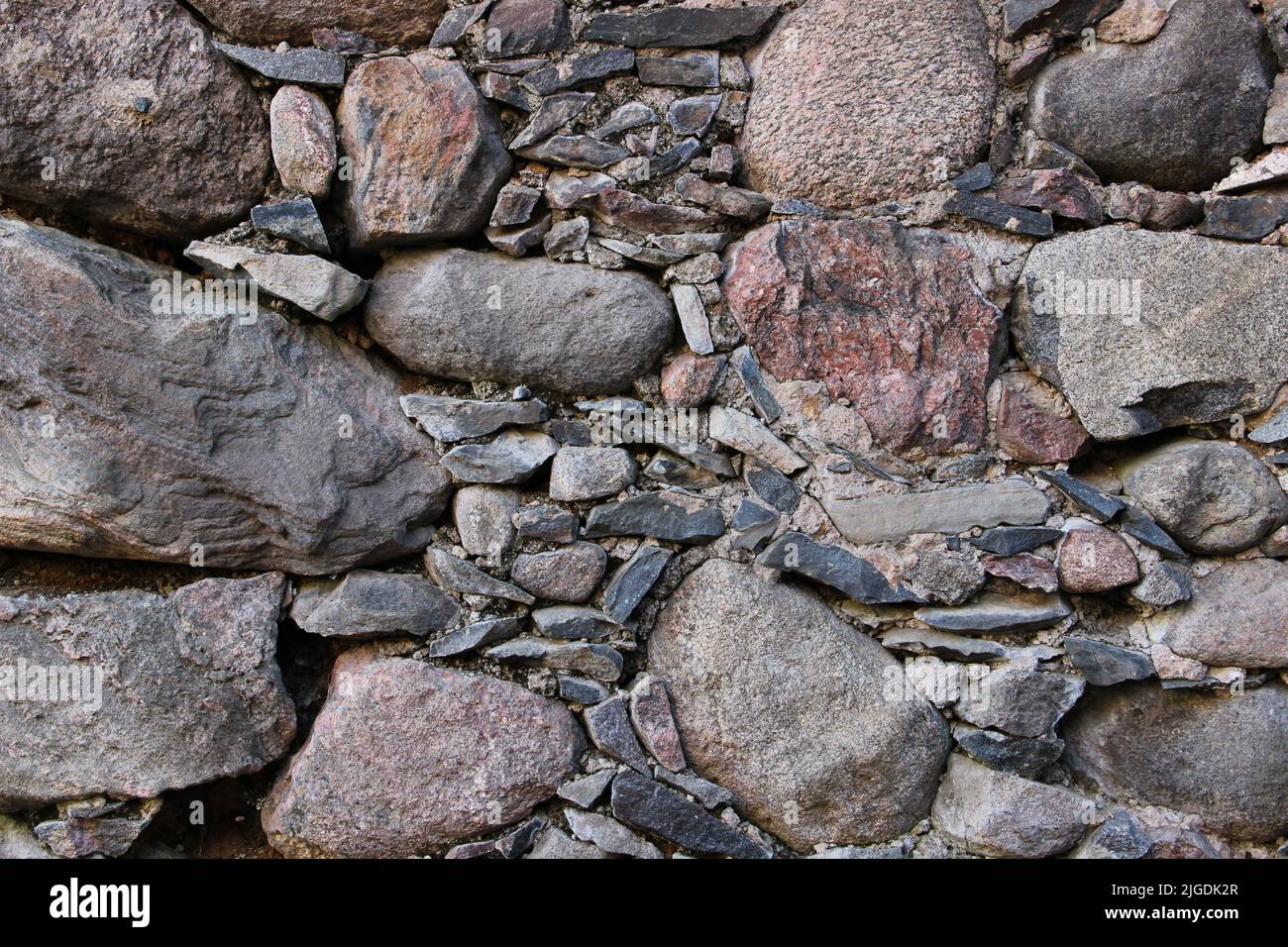 Old wall made of rocks. Medieval rocky surface. Old rocks are stucked ...