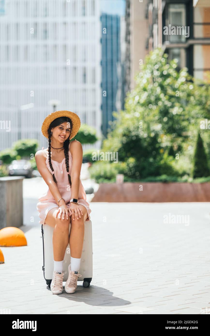 Young beautiful caucasian woman is sitting on suitecase Stock Photo - Alamy