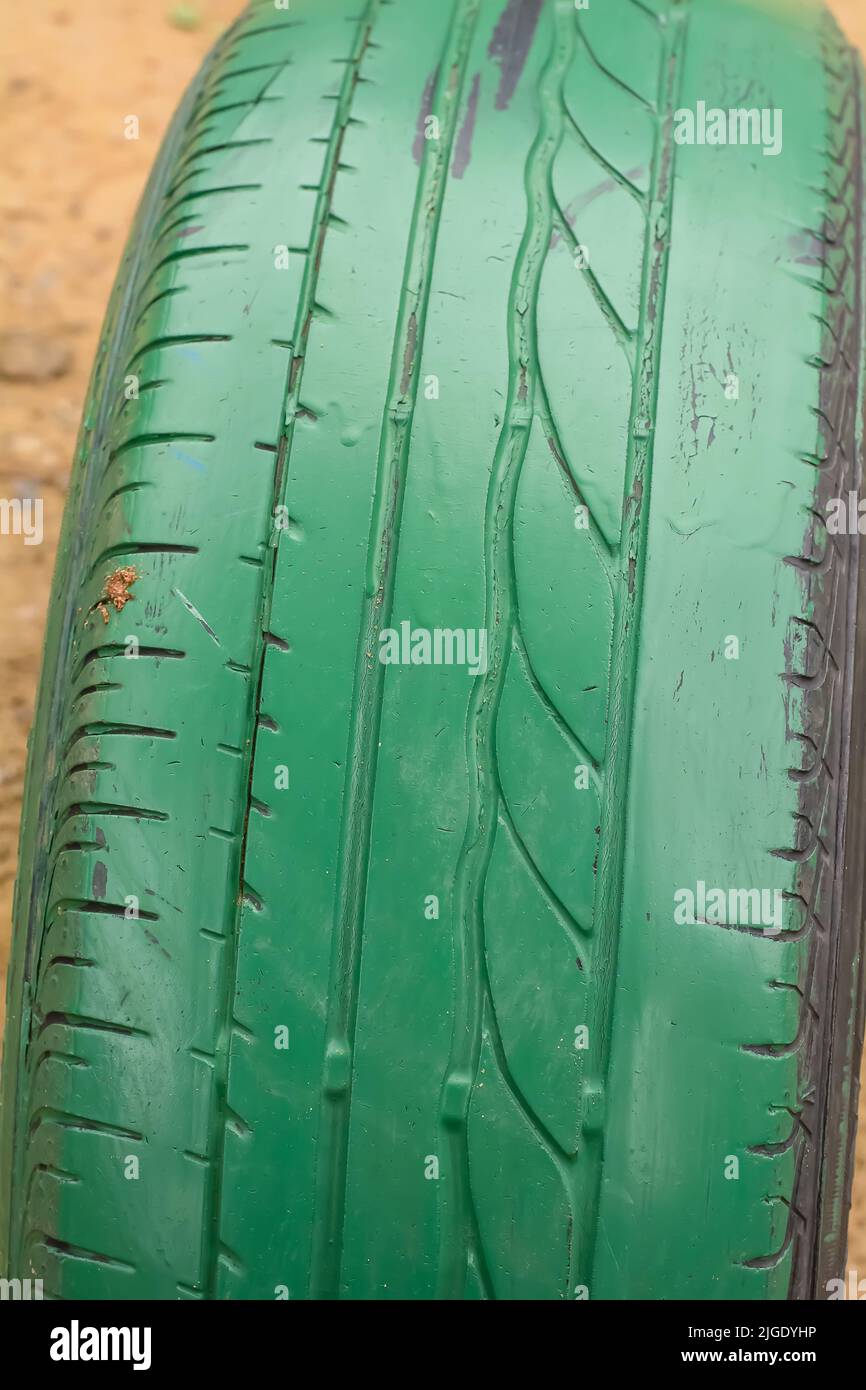 A vertical closeup of used car tires texture painted in green color ...