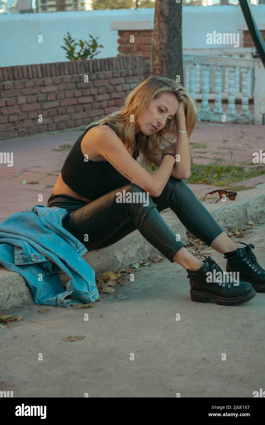 A vertical shot of thoughtful young female sitting on a curb Stock ...