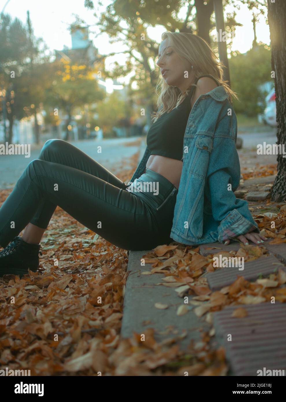 A beautiful young female sitting on a curb Stock Photo - Alamy
