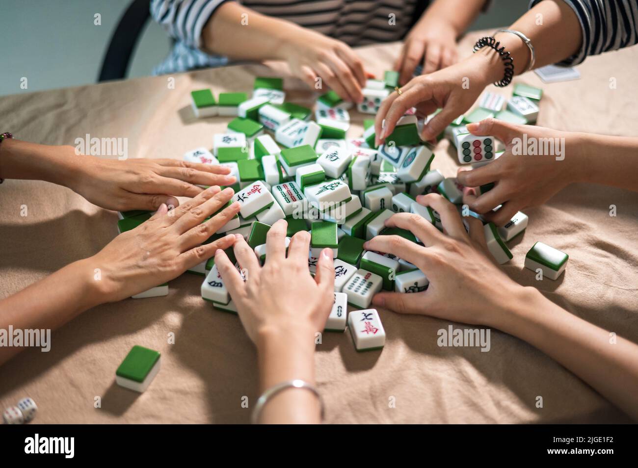 Female friends playing mahjong traditional Chinese board game at home ...