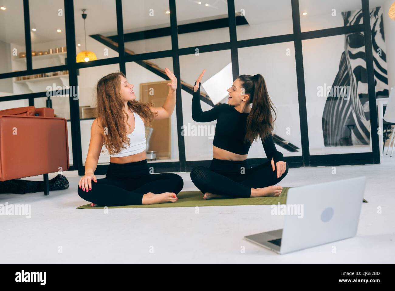 Two women while sitting in the lotus position give a high five Stock ...