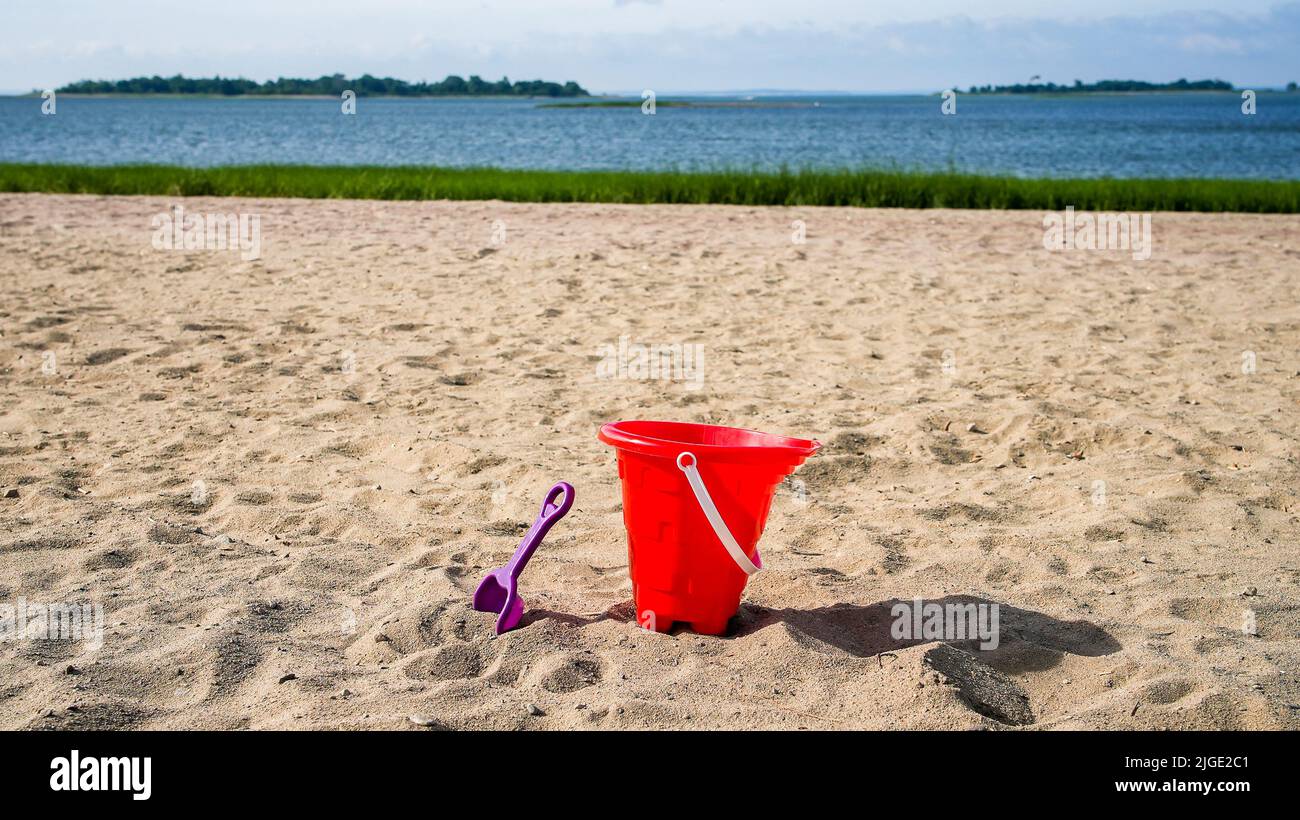 Toy shovel and red bucket on beach in summer day with beautiful sky ...