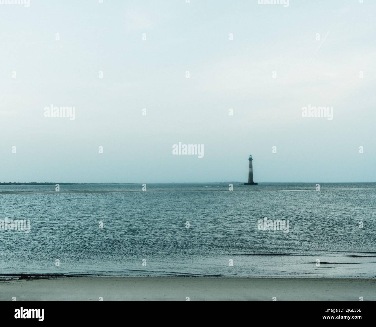 A lighthouse off the coast on a misty morning Stock Photo - Alamy