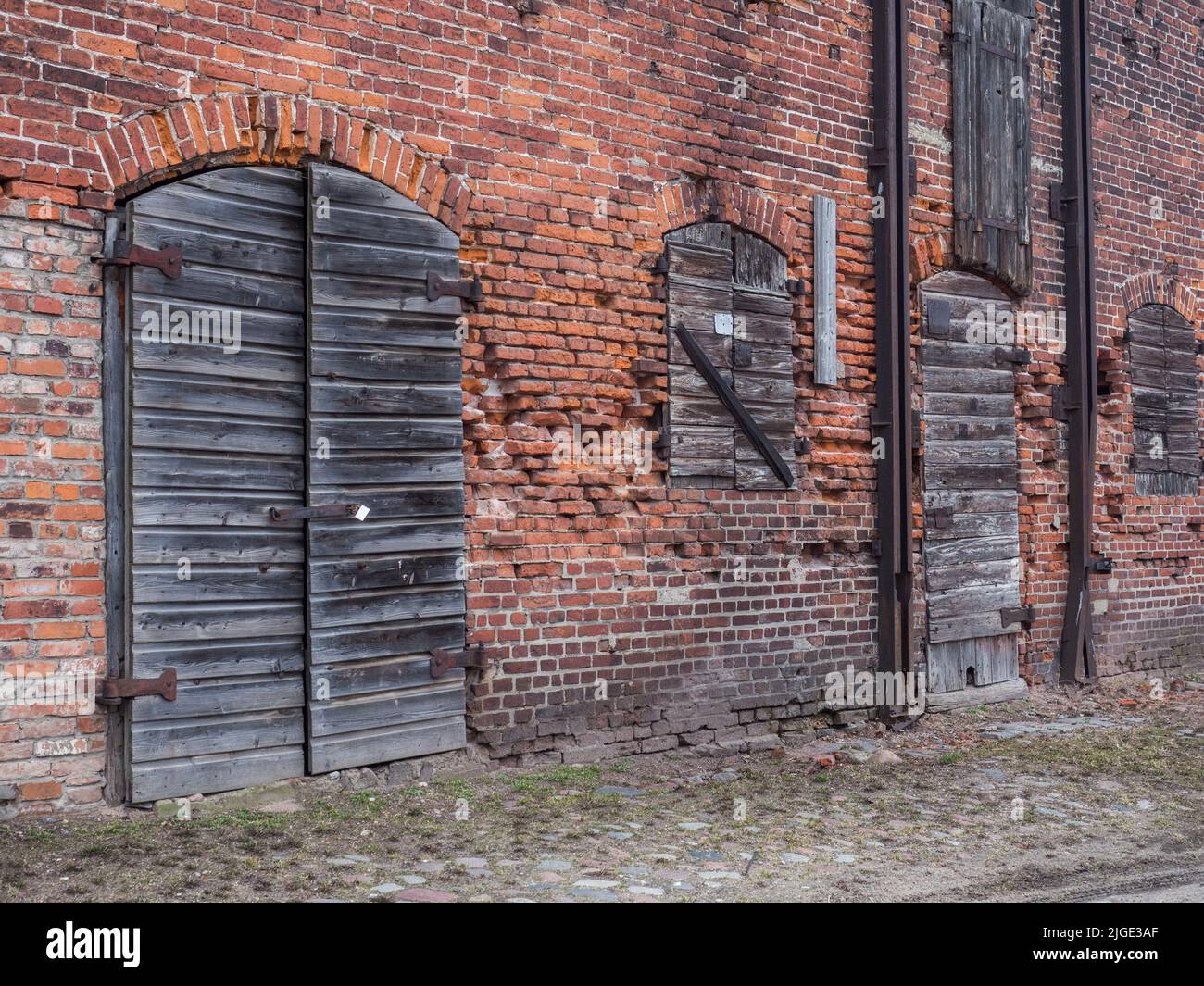 Red brick wall with wooden doors of old abandoned port warehouse ...