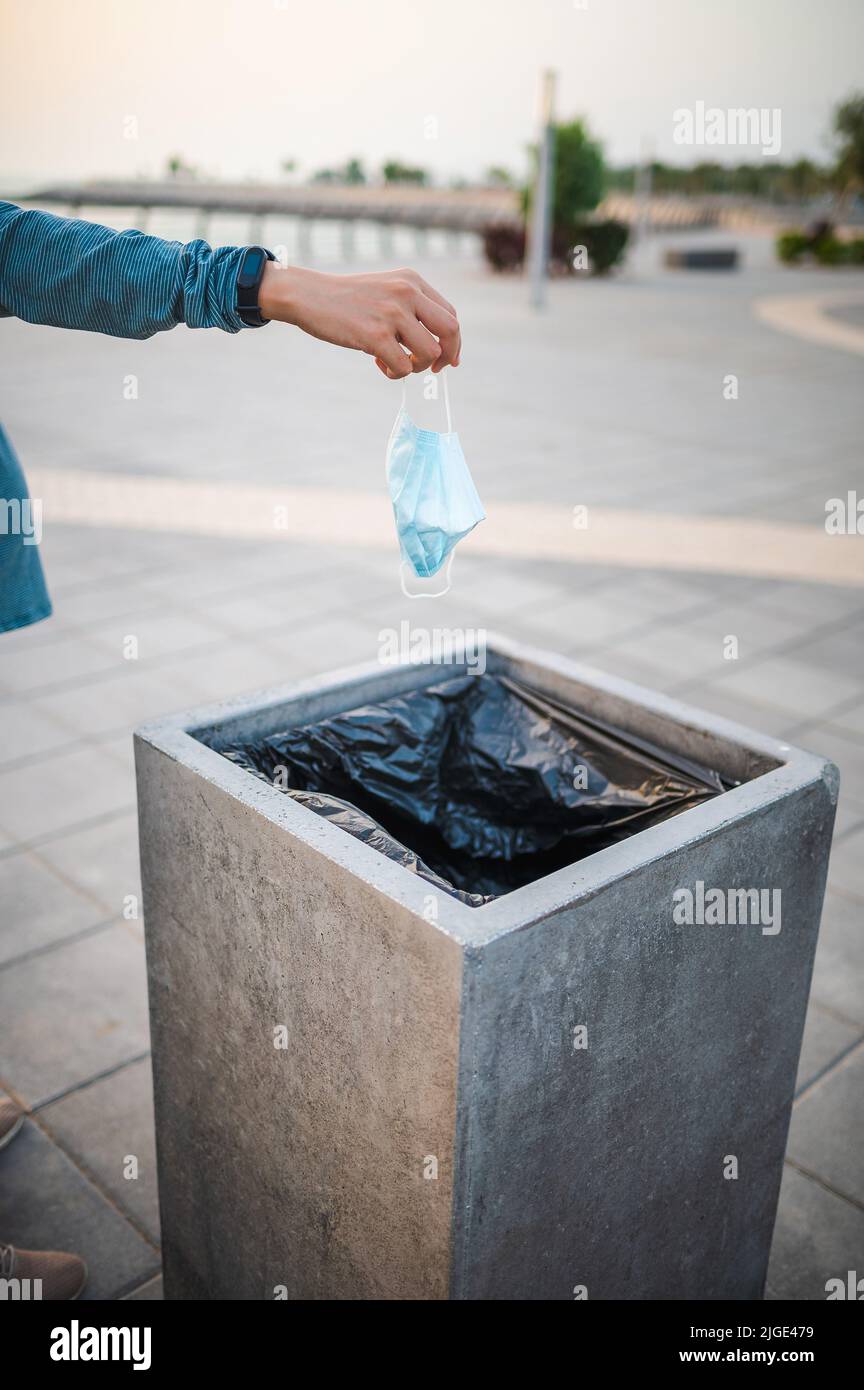 Unrecognizable pregnant woman throwing a used surgical medical face ...
