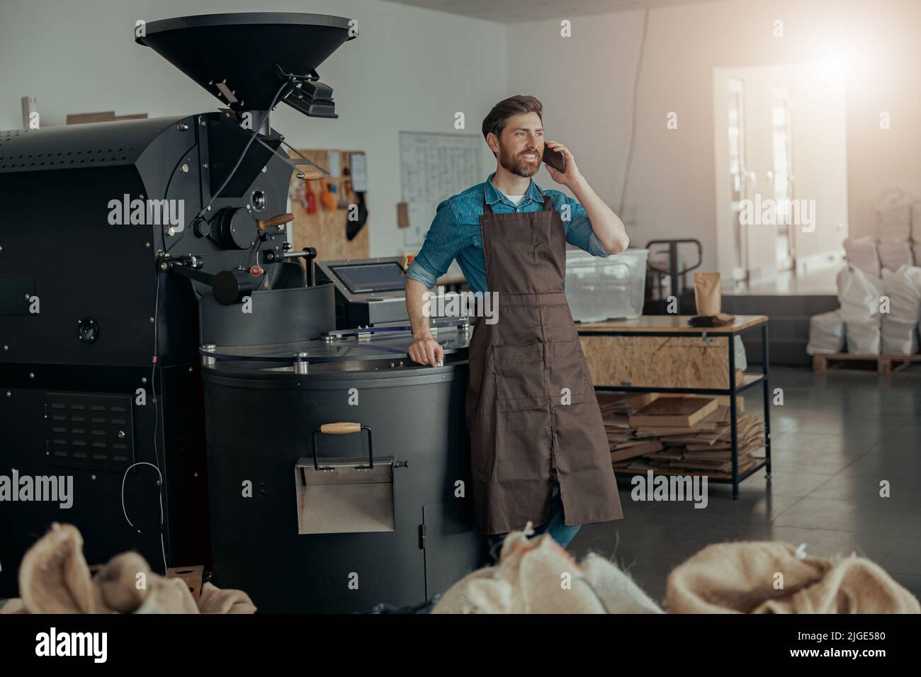Business owner of coffee factory talking phone on background of coffee ...