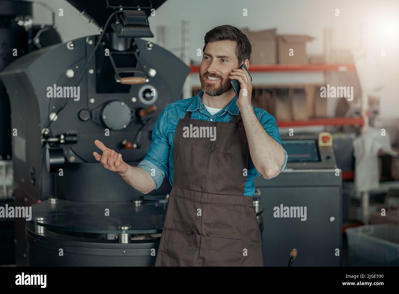 Business owner of coffee factory talking phone on background of coffee ...