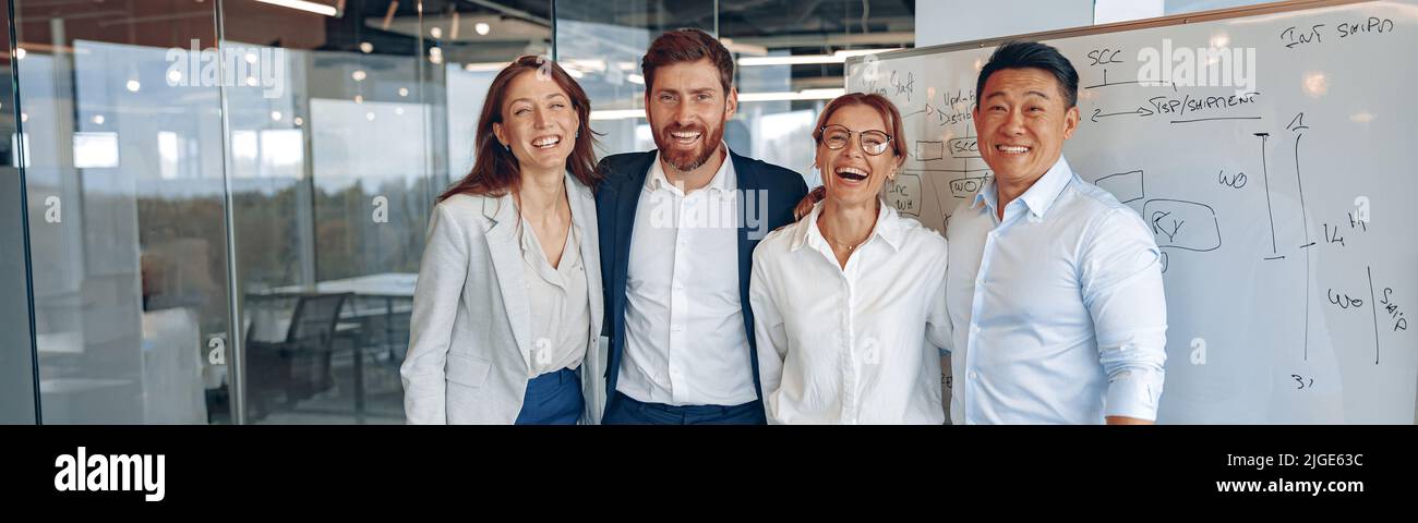 Happy diverse professional business team stand in office near board ...
