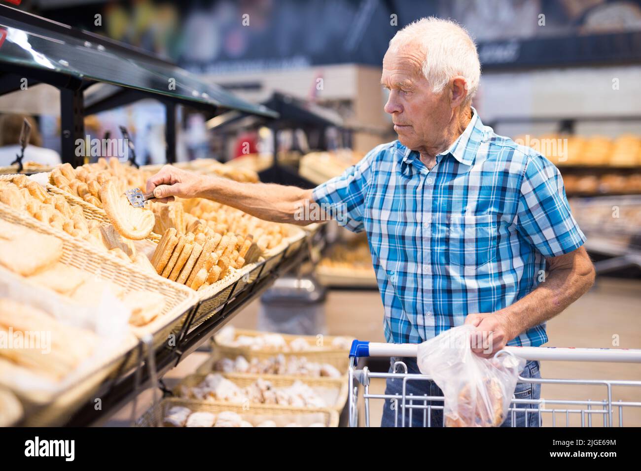 elderly man buying bread and pastries in grocery section of the ...