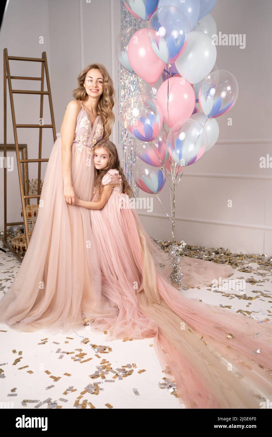 Young Beautiful Mother And Preschooler Daughter Stand Dressed In Pink