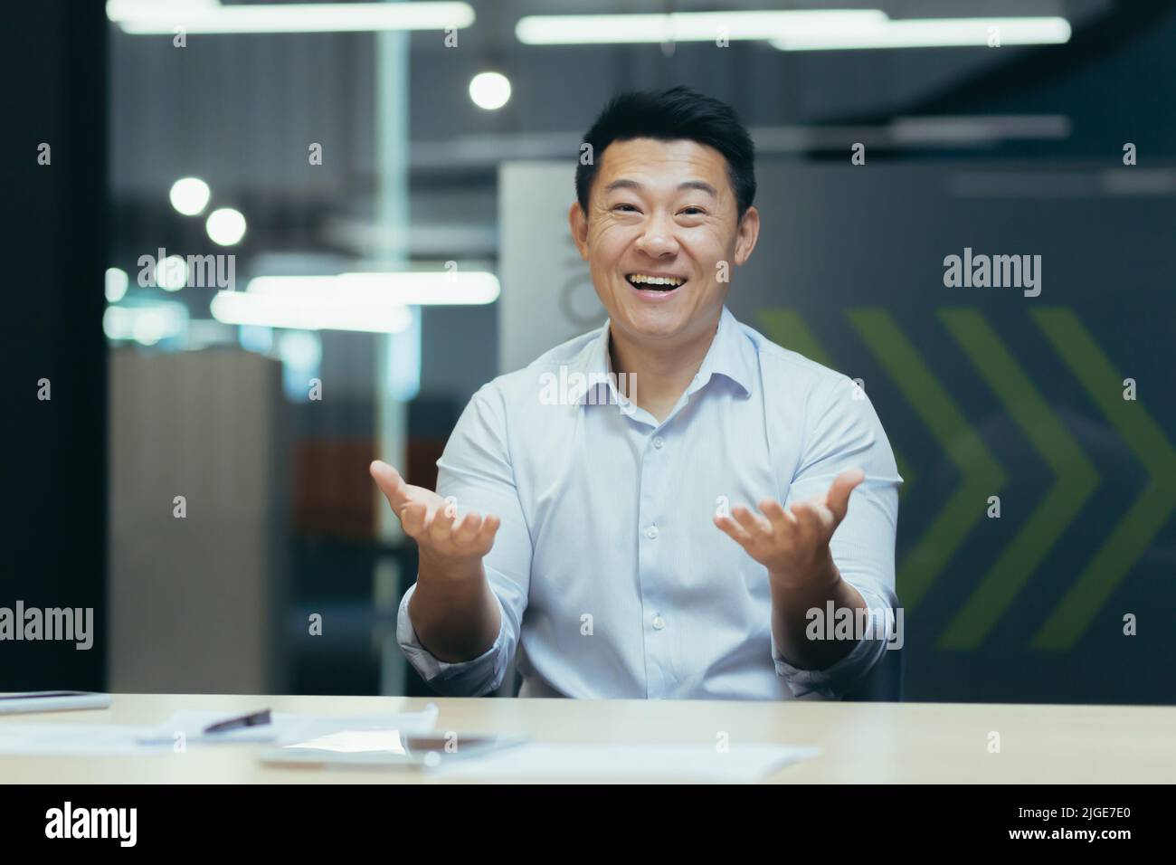 Successful and happy Asian businessman looking at camera, talking on ...
