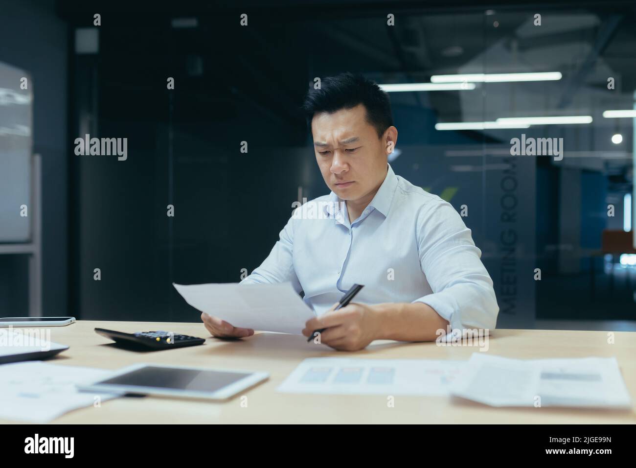 Upset and unhappy asian businessman reading documents and letter from ...