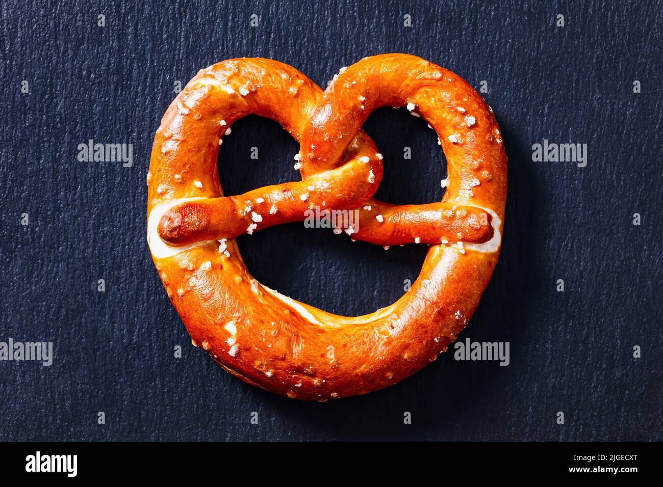 soft pretzel baked in the form of knot and sprinkled with salt on black ...