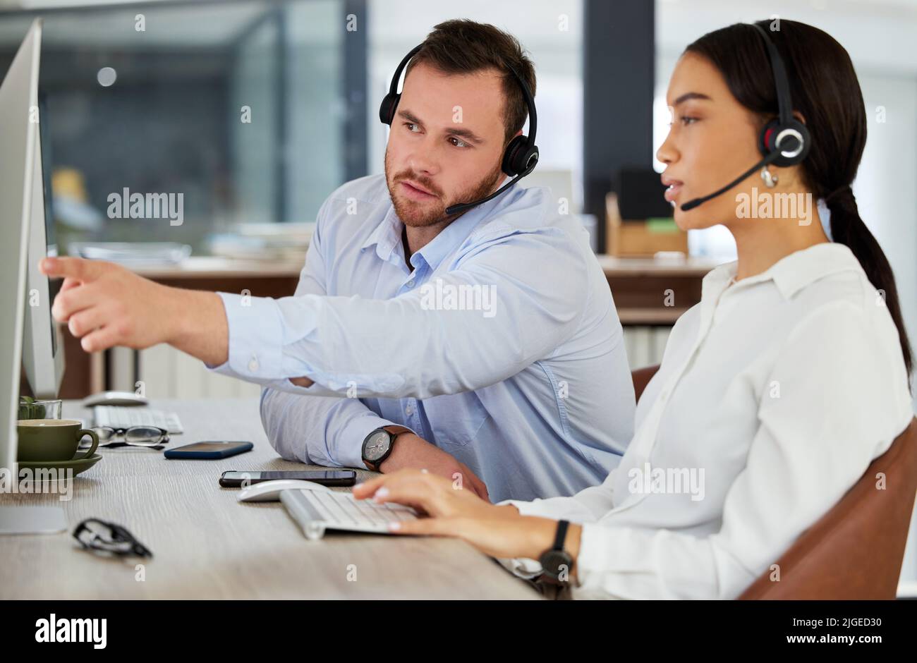 Teamwork makes the call work. a young man and woman using a computer ...