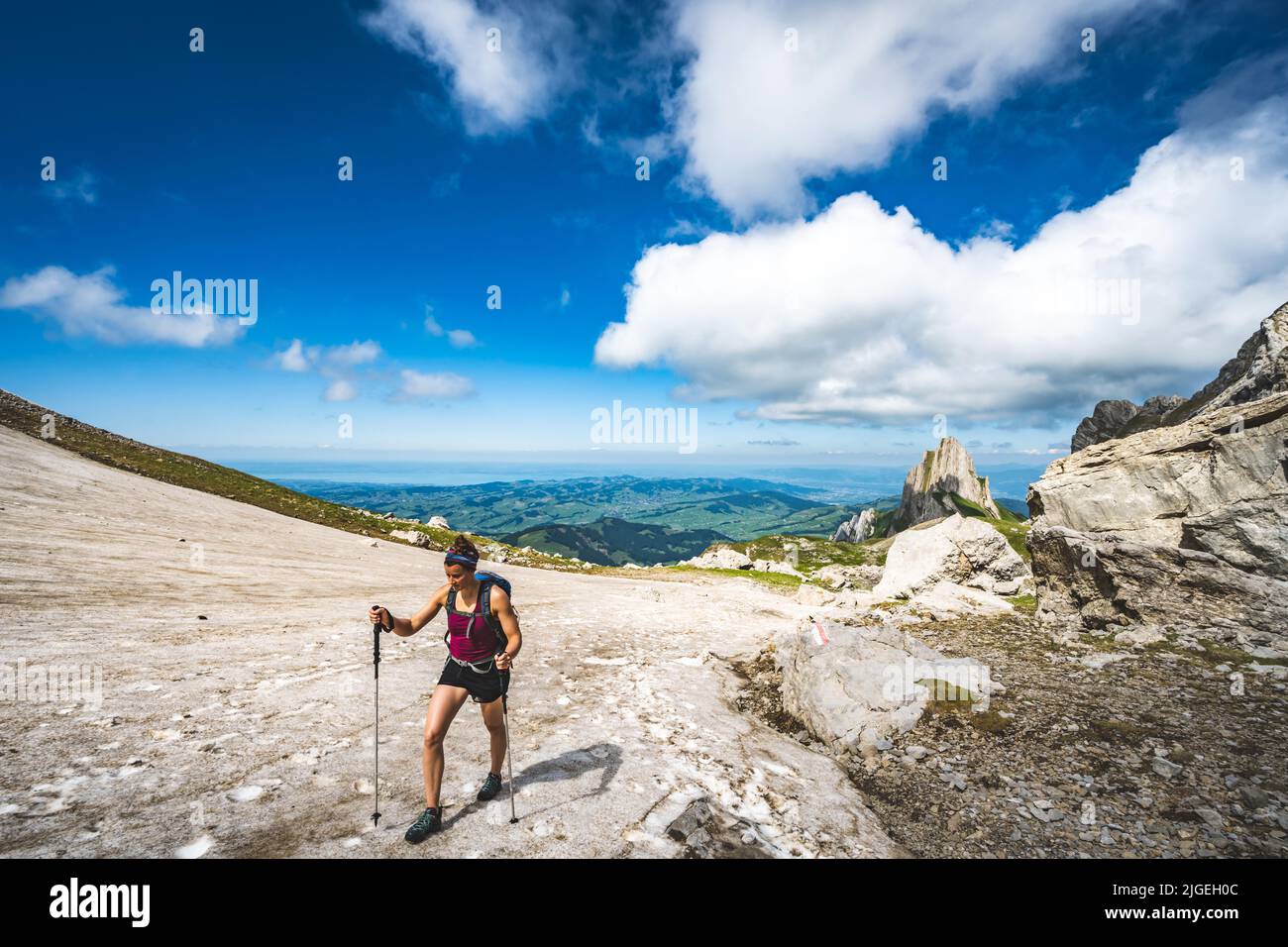 Hiker is crossing a snow field on the ascend to Öhrli, a peak in ...
