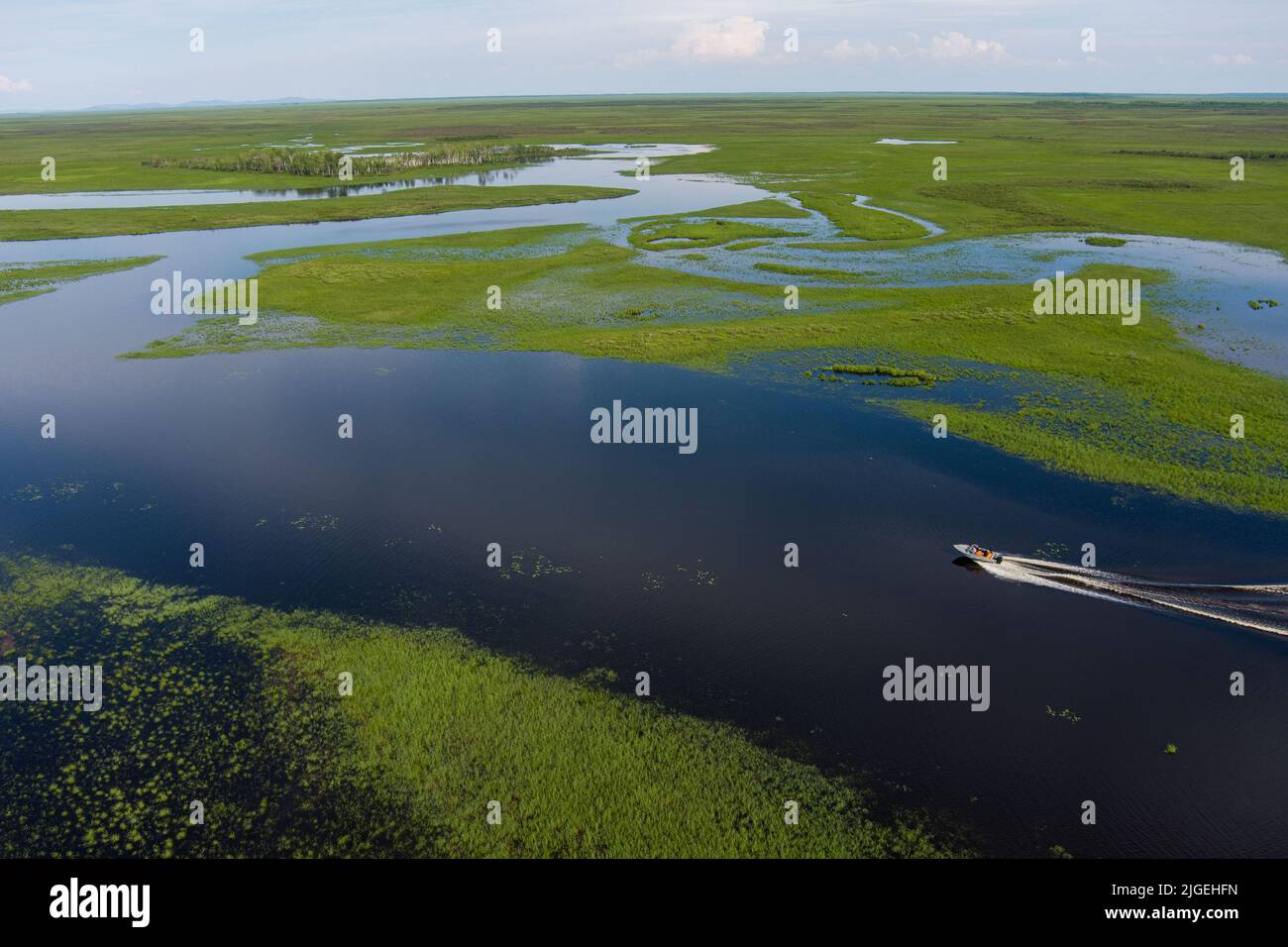A photo from a drone over the river with a speedboat at sunset. A bird ...