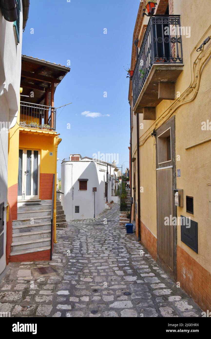 A narrow street between the old houses of Grottole, a village in the ...