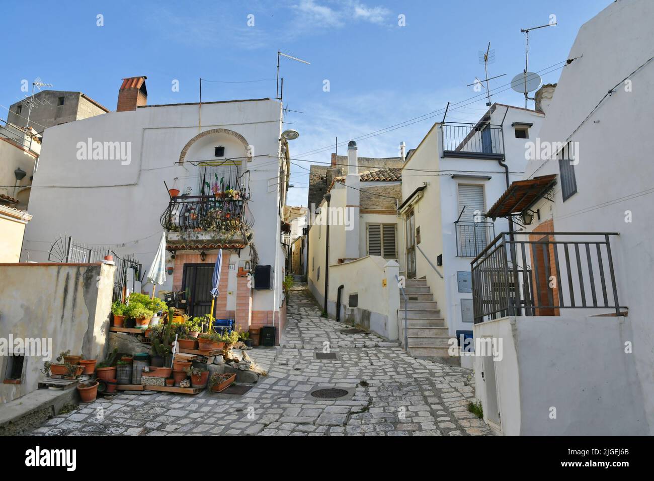 A narrow street between the old houses of Grottole, a village in the ...